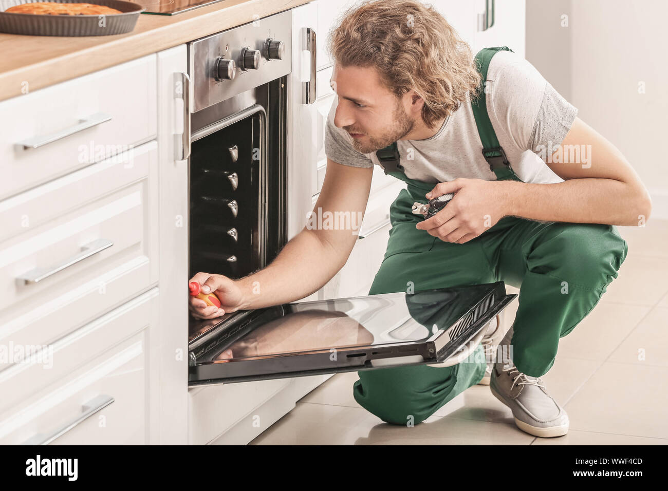 Worker repairing oven in kitchen Stock Photo - Alamy