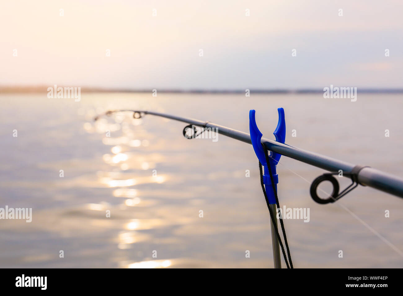 Modern fishing rod on holder near river Stock Photo - Alamy
