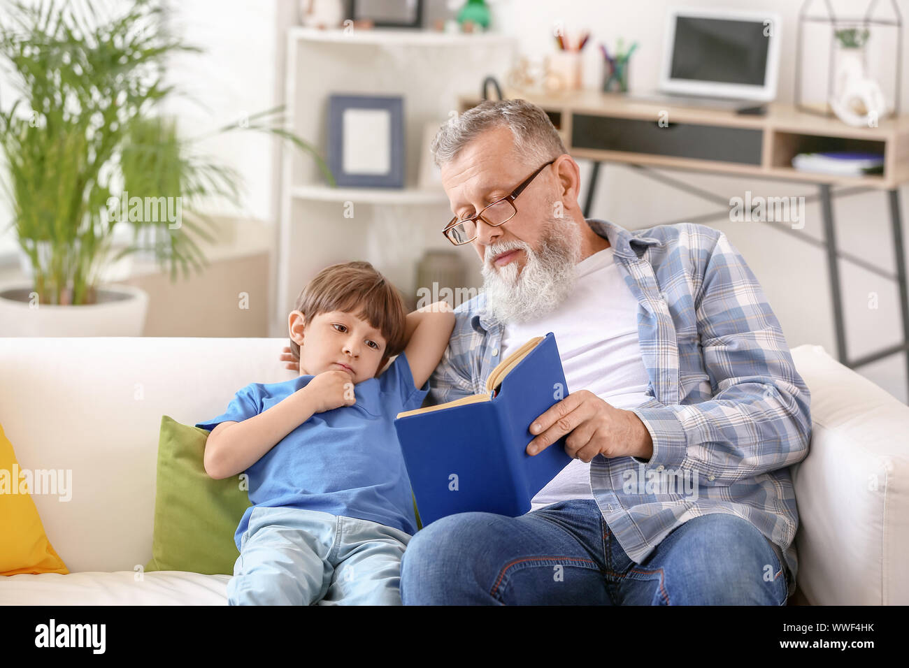Cute little boy reading book with grandfather at home Stock Photo - Alamy