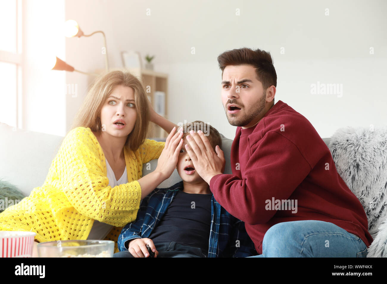 Family watching scary movie at home Stock Photo - Alamy