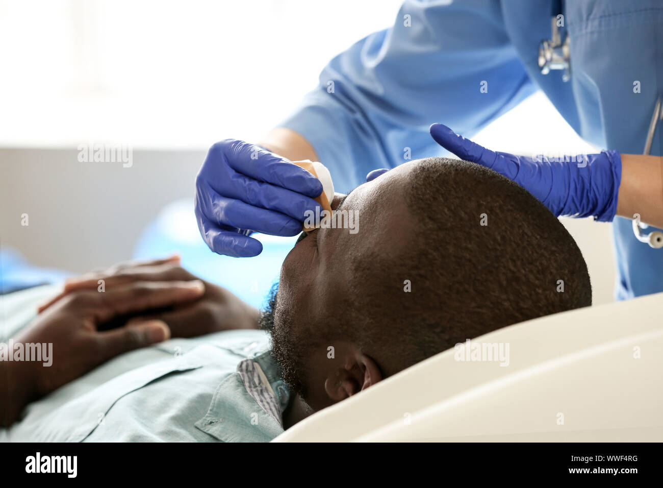 Plastic surgeon examining African-American man after operation in ...