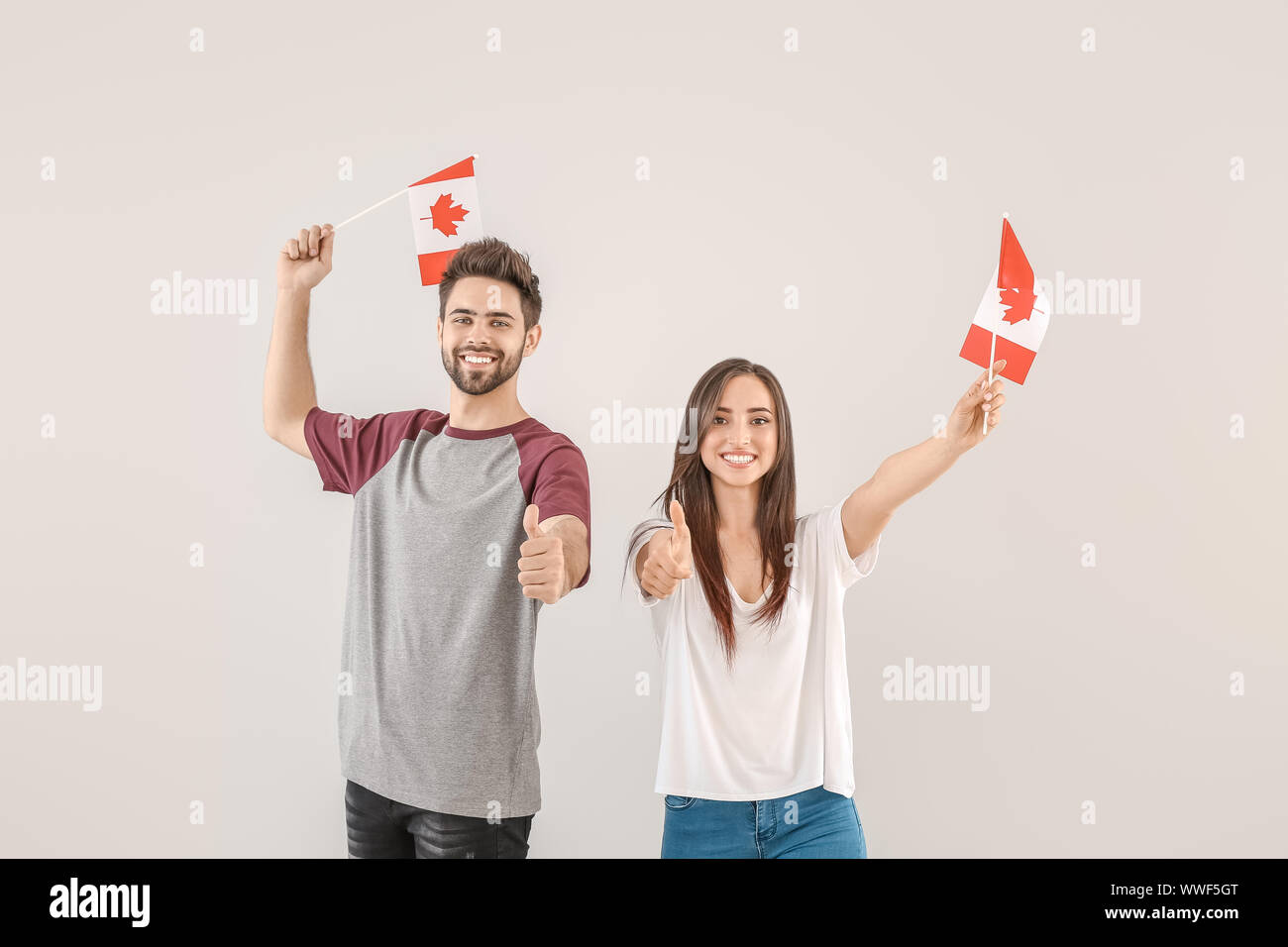 Young people with Canadian flags on light background Stock Photo - Alamy