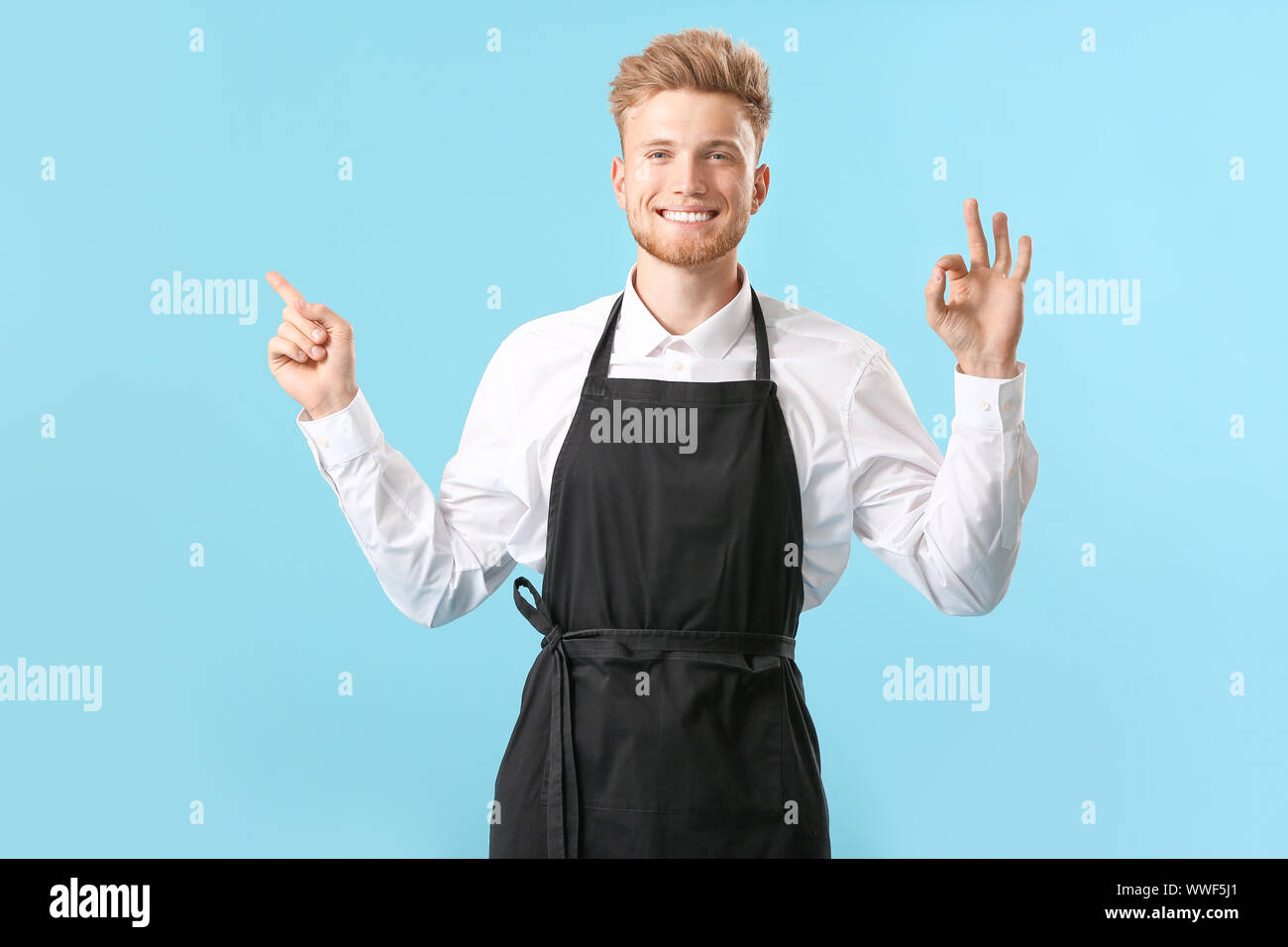 Handsome male chef pointing at something and showing OK on color ...