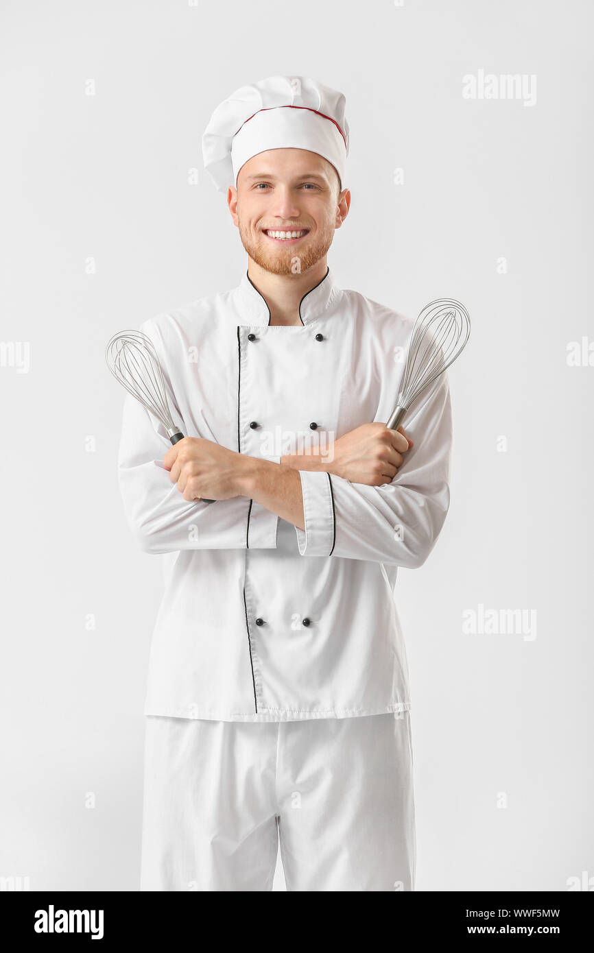Handsome male chef with whisks on white background Stock Photo - Alamy