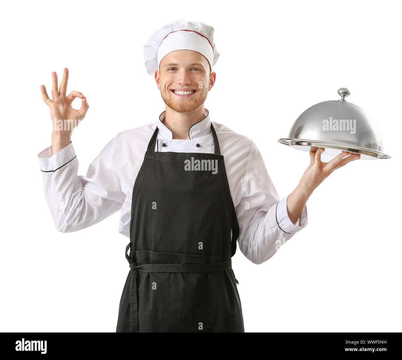 Handsome male chef with tray and cloche showing OK on white background ...