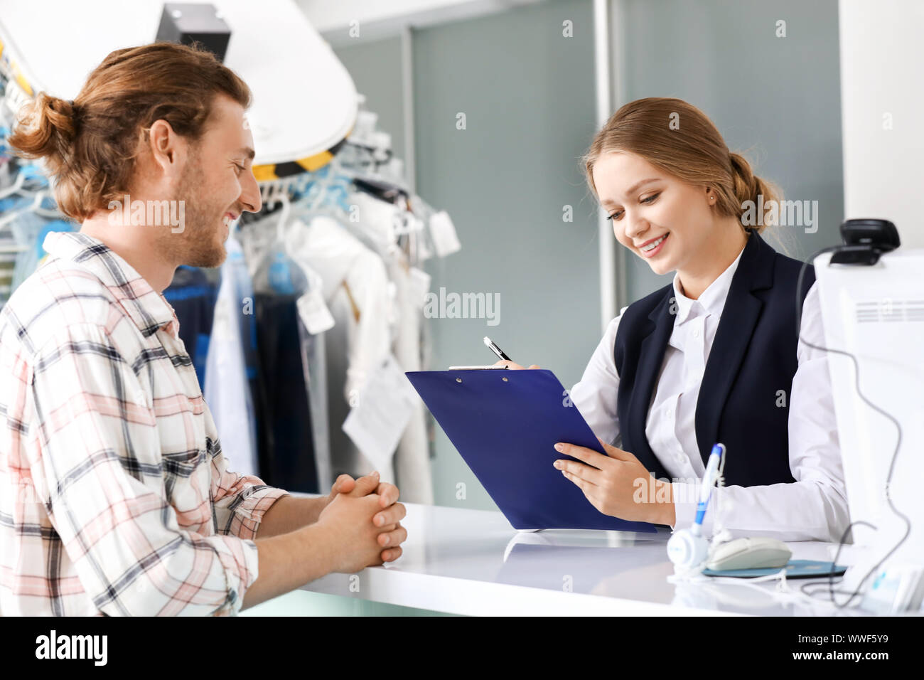 Client near reception desk of modern dry-cleaner's Stock Photo - Alamy