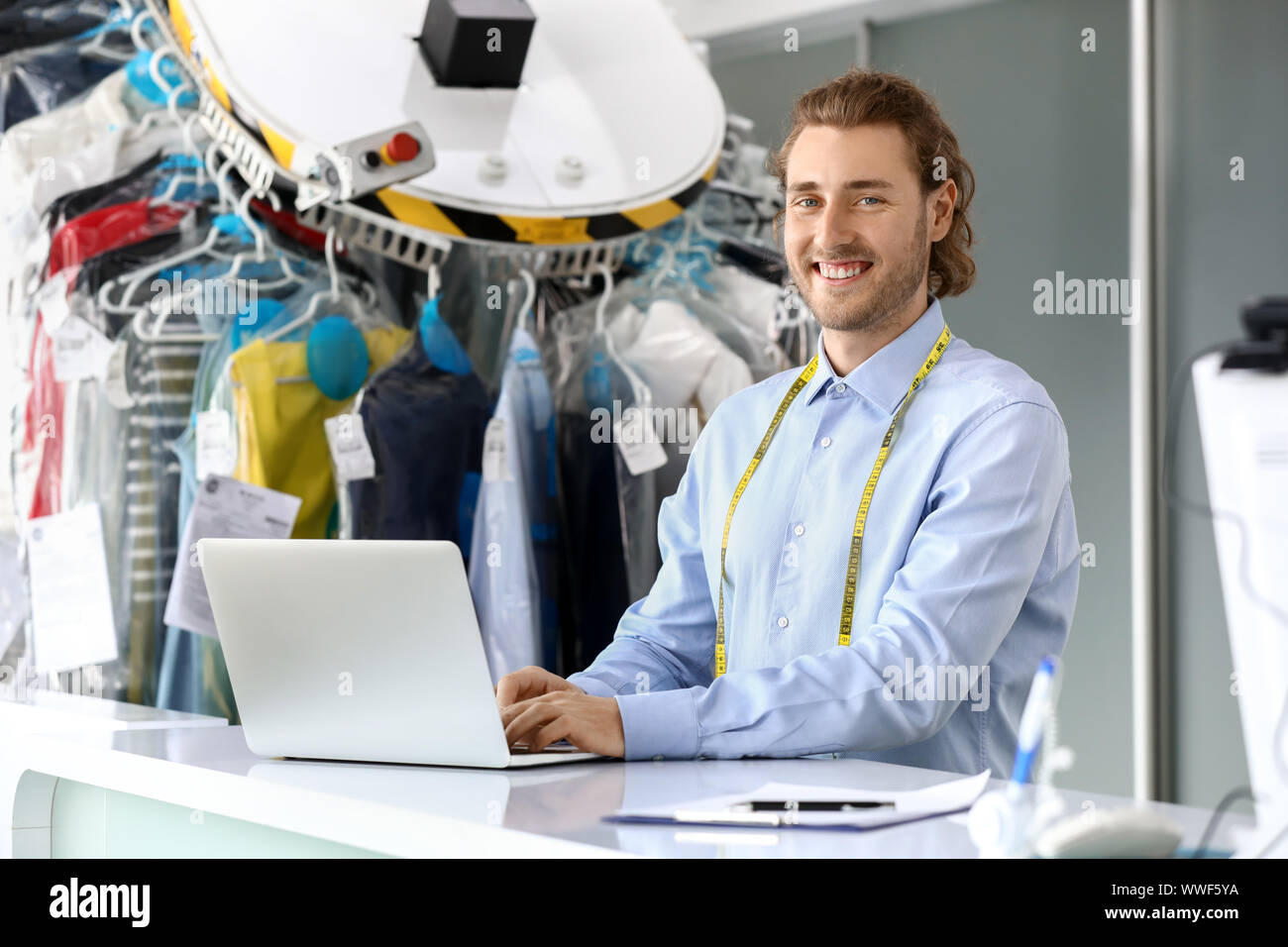 Worker of modern dry-cleaner's at reception Stock Photo - Alamy