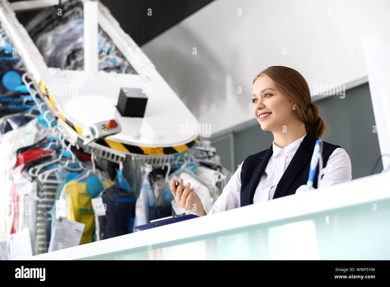 Worker of modern dry-cleaner's at reception Stock Photo - Alamy