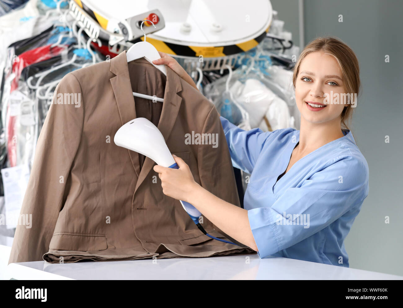 Worker of modern dry-cleaner's steaming clothes Stock Photo - Alamy