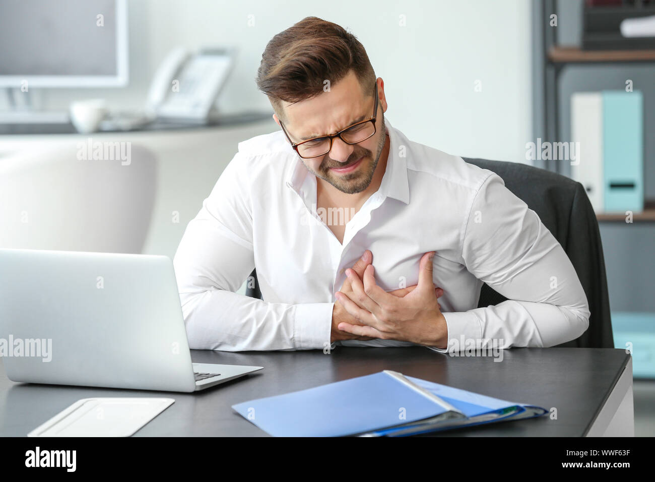 Young businessman having heart attack in office Stock Photo - Alamy