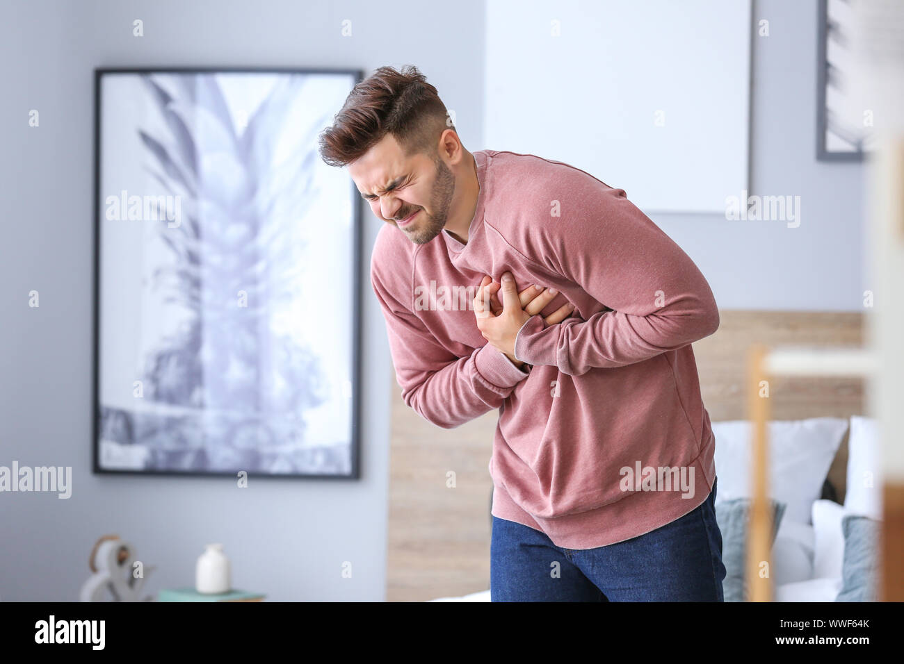 Young man suffering from heart attack at home Stock Photo - Alamy