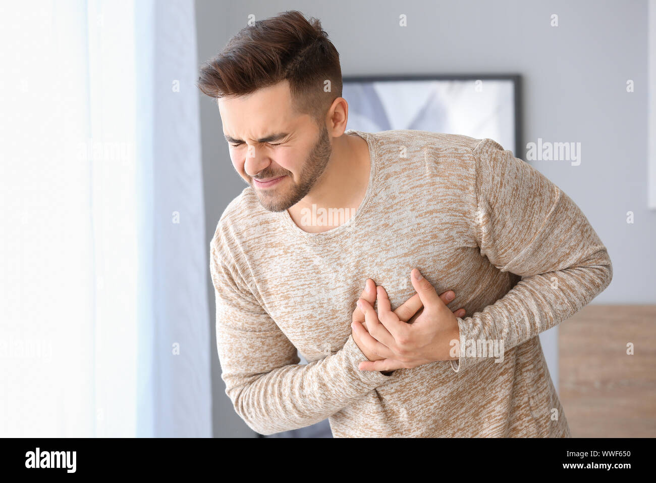 Young man suffering from heart attack at home Stock Photo - Alamy