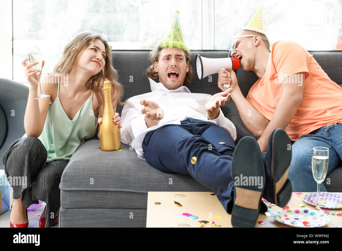 Young man with megaphone playing prank with his friend after party ...
