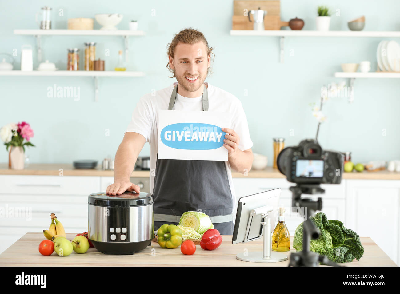 Food blogger announcing prize drawing while recording video in kitchen ...