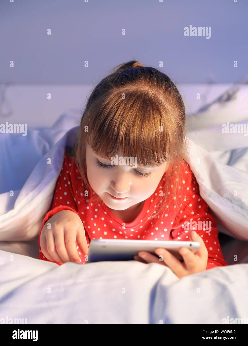 Cute little girl using tablet computer in bed at night Stock Photo - Alamy