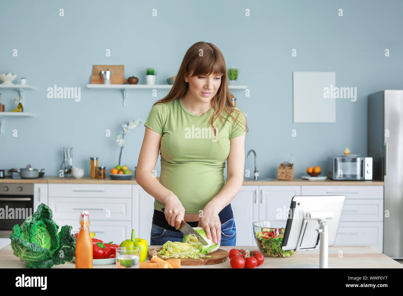 Young pregnant woman cooking in kitchen Stock Photo - Alamy
