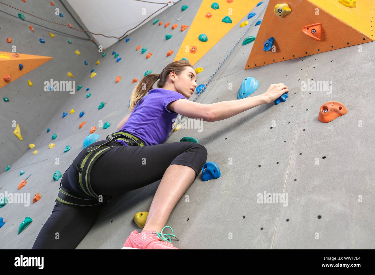 Young woman climbing wall in gym Stock Photo - Alamy
