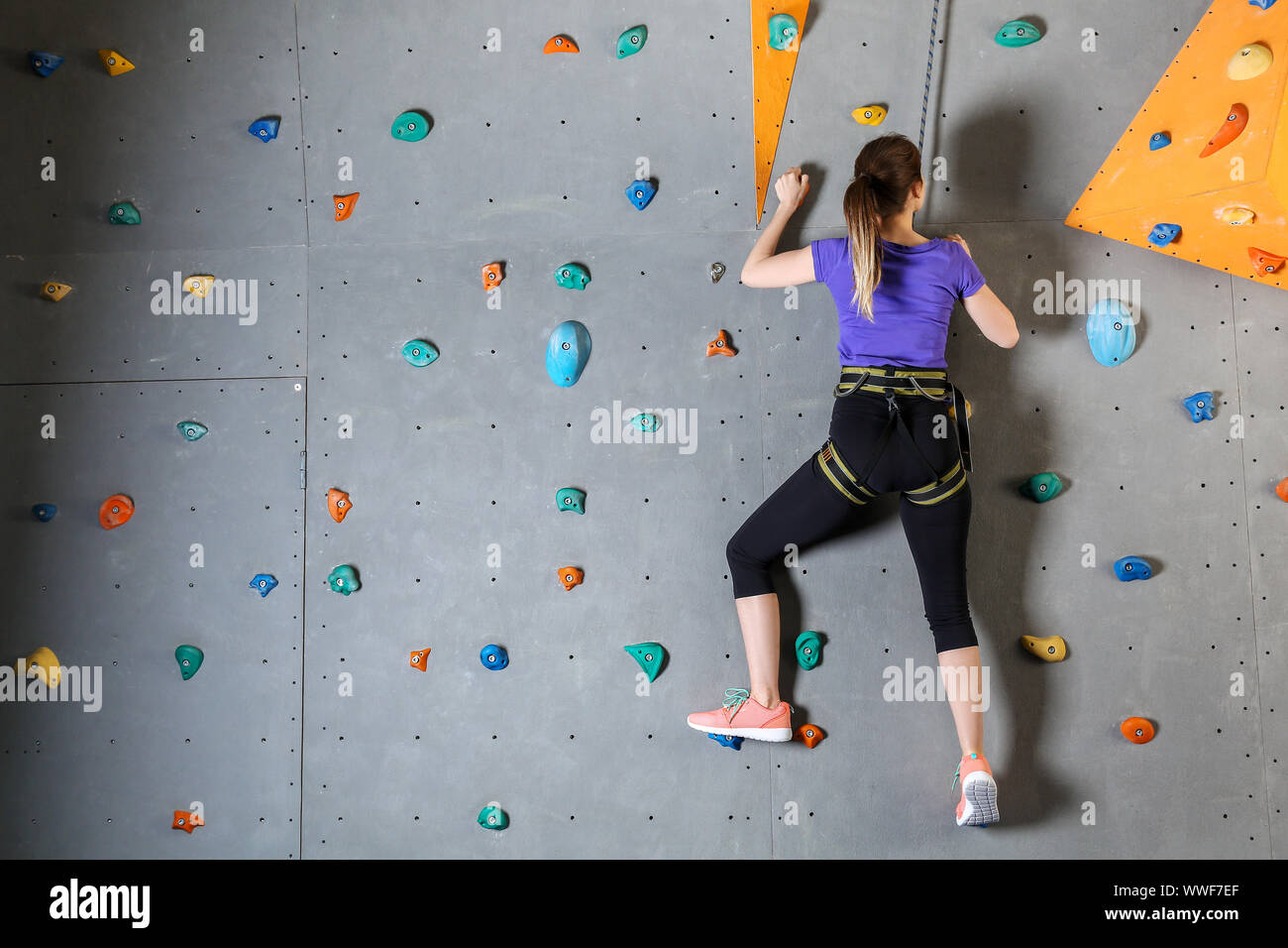 Young woman climbing wall in gym Stock Photo - Alamy