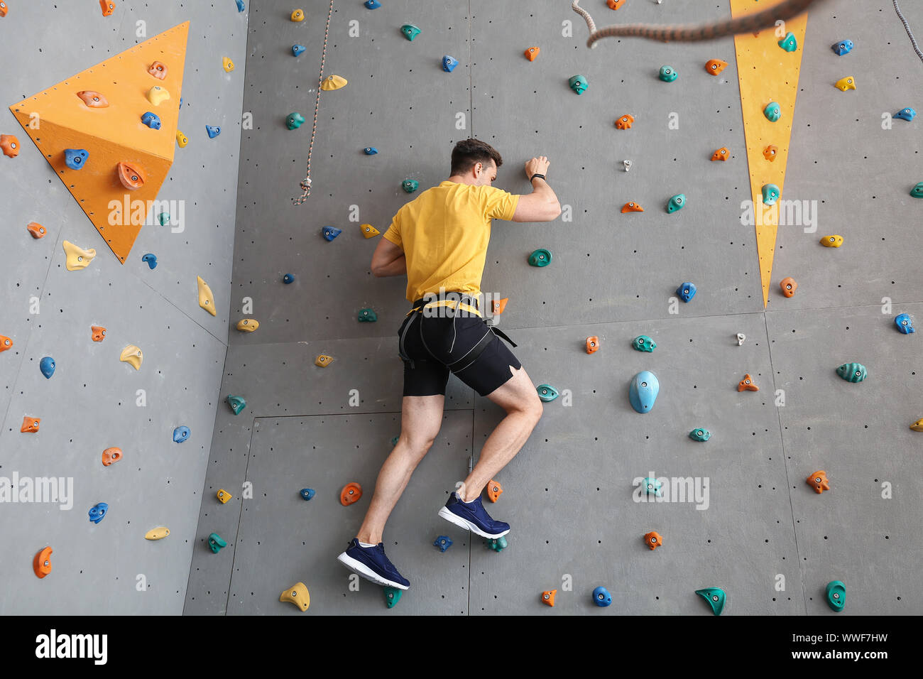Young man climbing wall in gym Stock Photo - Alamy