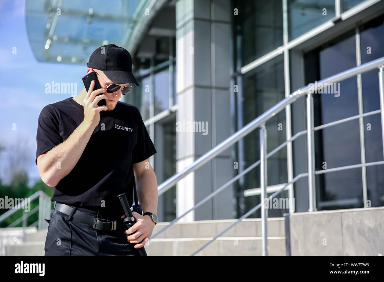 Handsome male security guard talking by phone outdoors Stock Photo - Alamy
