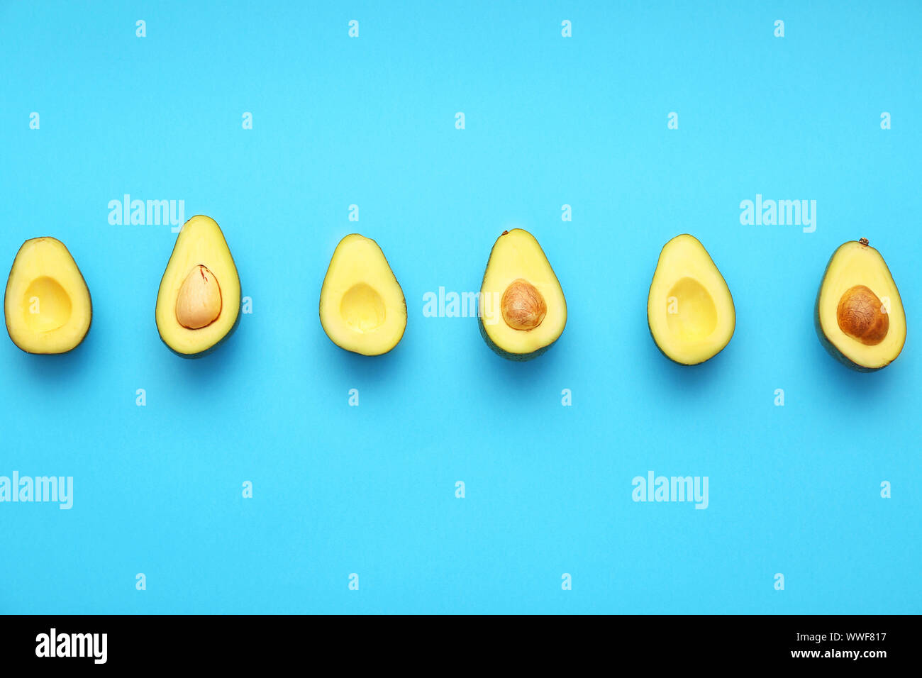 Halves of fresh avocados on color background Stock Photo - Alamy
