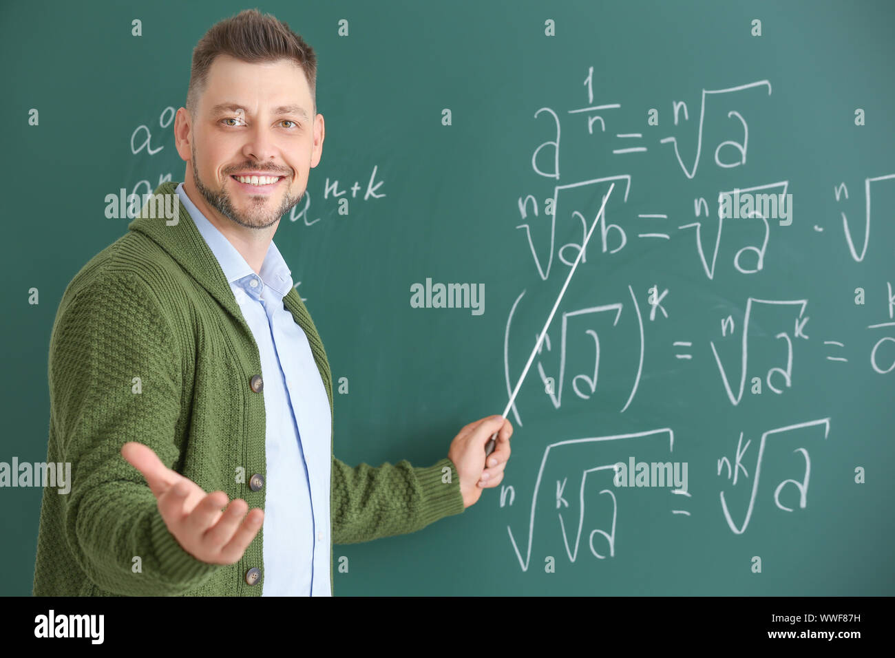 Handsome math teacher near blackboard in classroom Stock Photo - Alamy