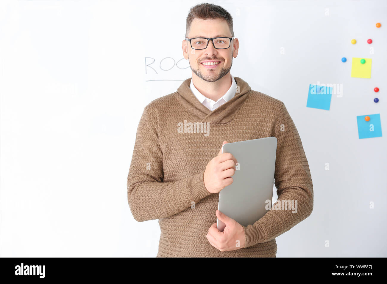 Handsome male teacher with laptop near blackboard in classroom Stock ...