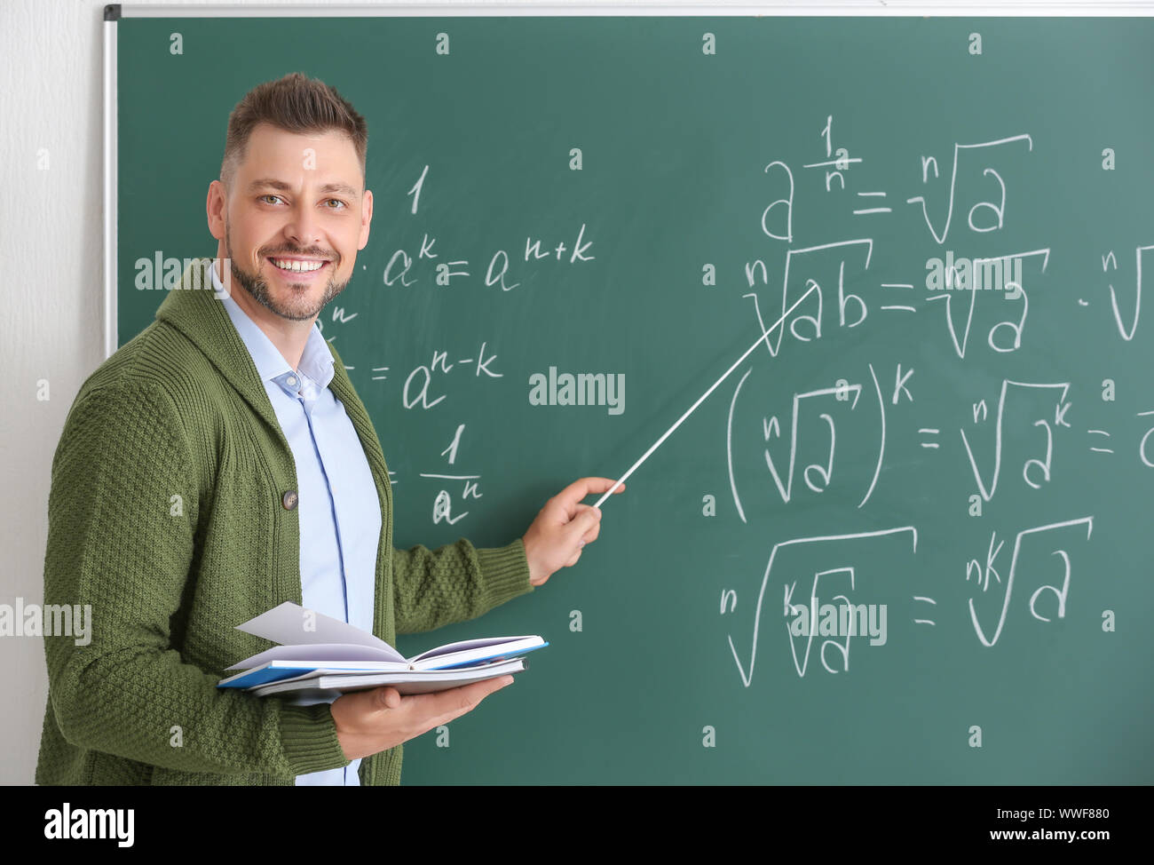 Handsome math teacher near blackboard in classroom Stock Photo - Alamy