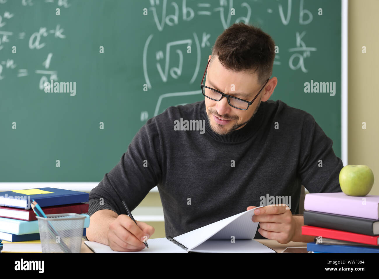 Handsome male teacher checking homework in classroom Stock Photo - Alamy