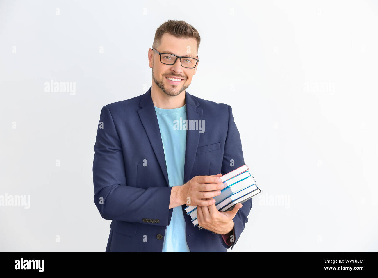 Handsome male teacher with books on light background Stock Photo - Alamy