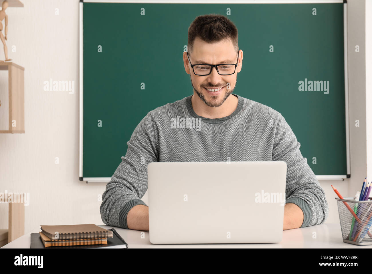 Handsome male teacher with laptop in classroom Stock Photo - Alamy