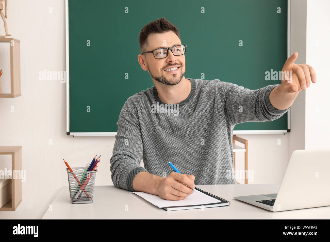 Handsome male teacher calling out pupil during lesson in classroom ...