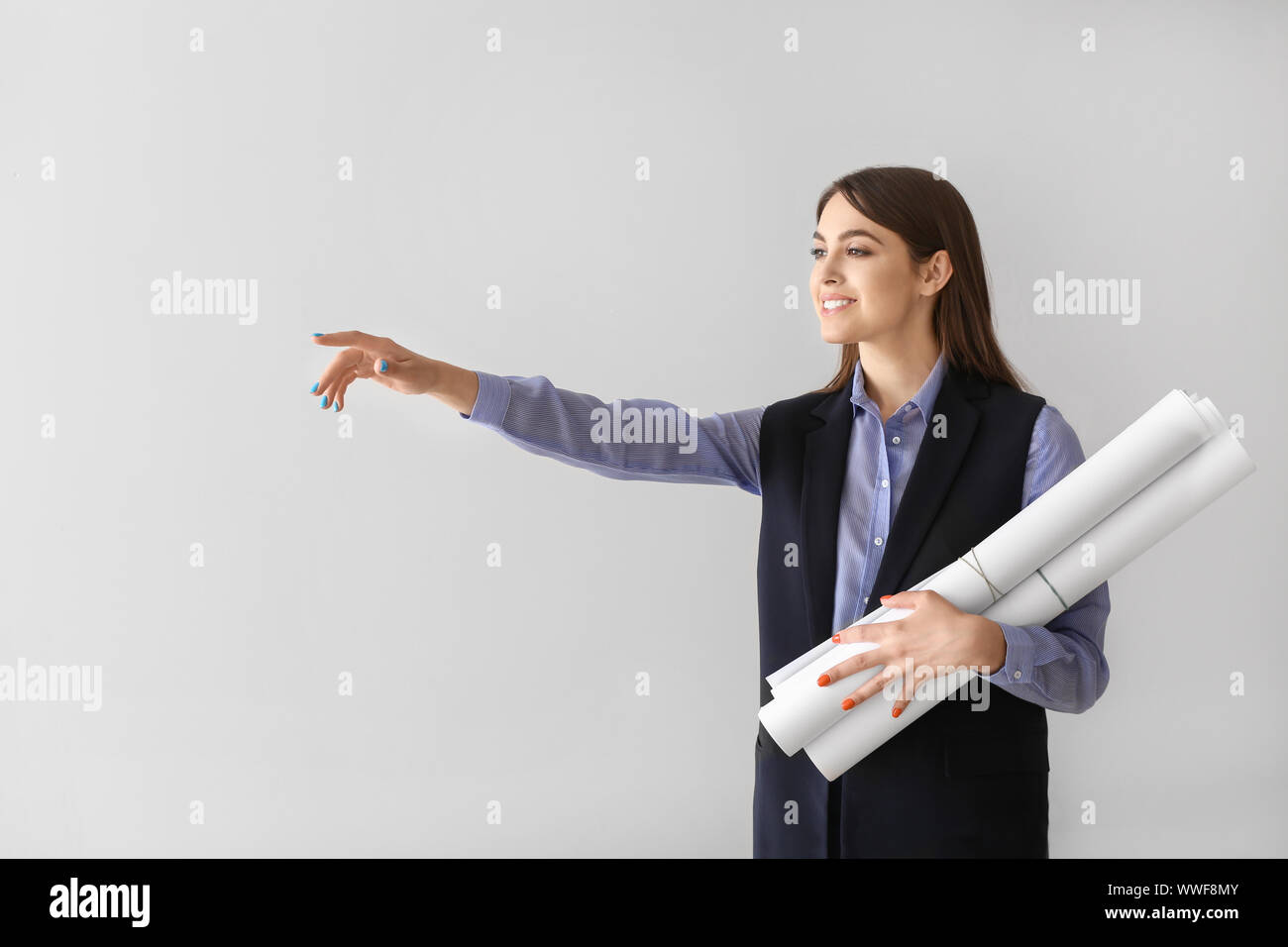 Beautiful female architect pointing at something on white background ...