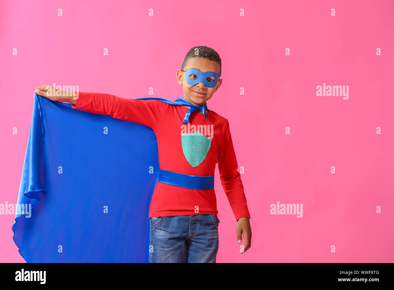 Cute African-American boy dressed as superhero on color background ...