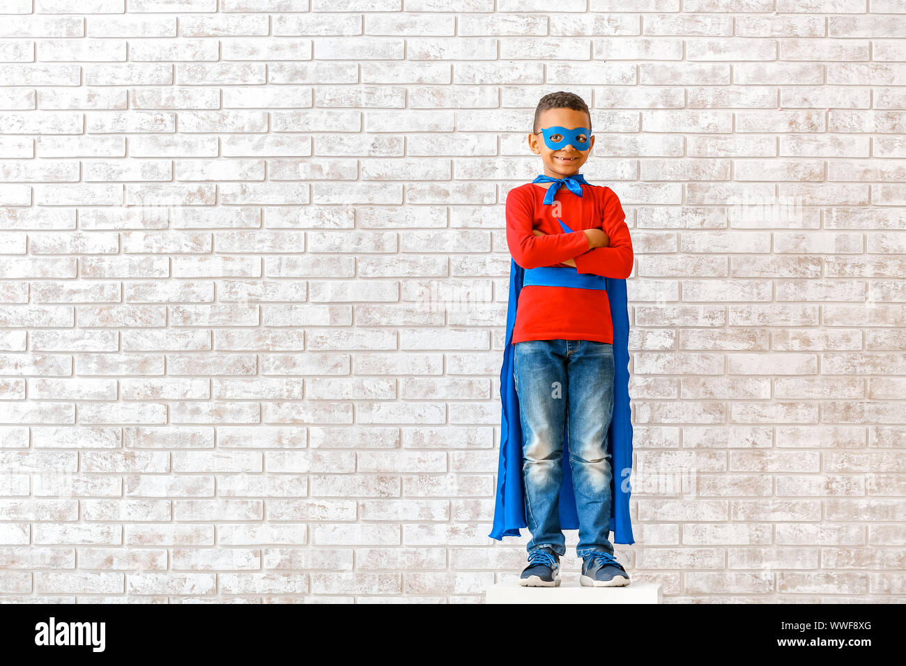 Cute African-American boy dressed as superhero near brick wall Stock ...