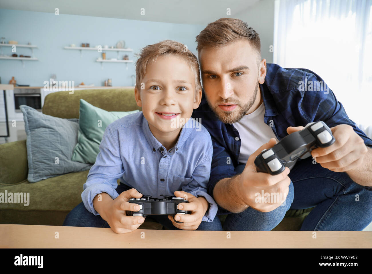 Portrait of father and son playing video game at home Stock Photo - Alamy