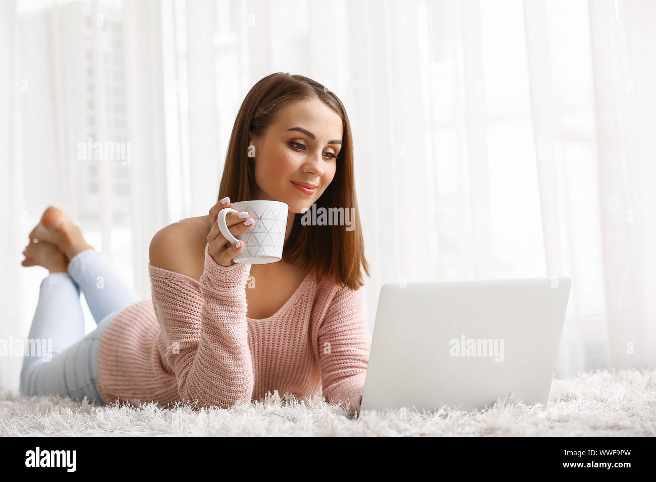 Beautiful young woman with laptop drinking tea at home Stock Photo - Alamy