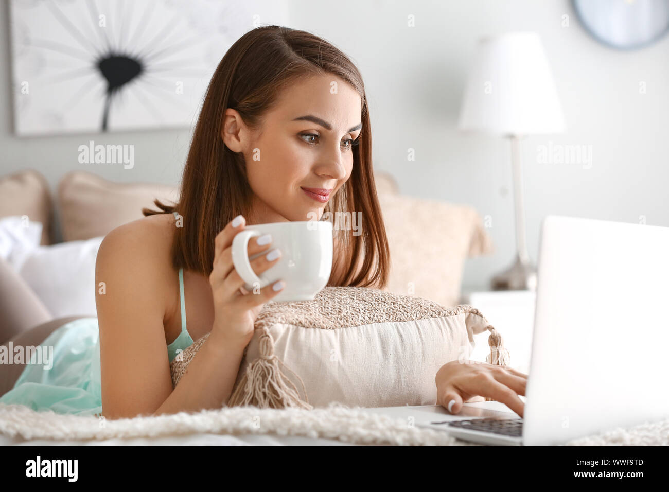 Beautiful young woman with laptop drinking tea at home Stock Photo - Alamy