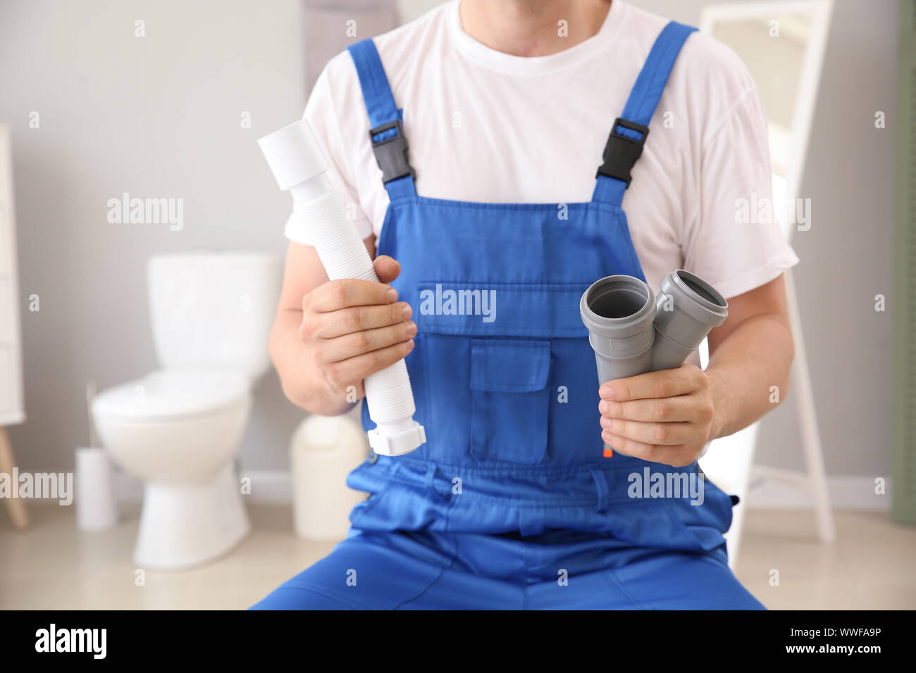 Plumber with pipes in restroom Stock Photo - Alamy