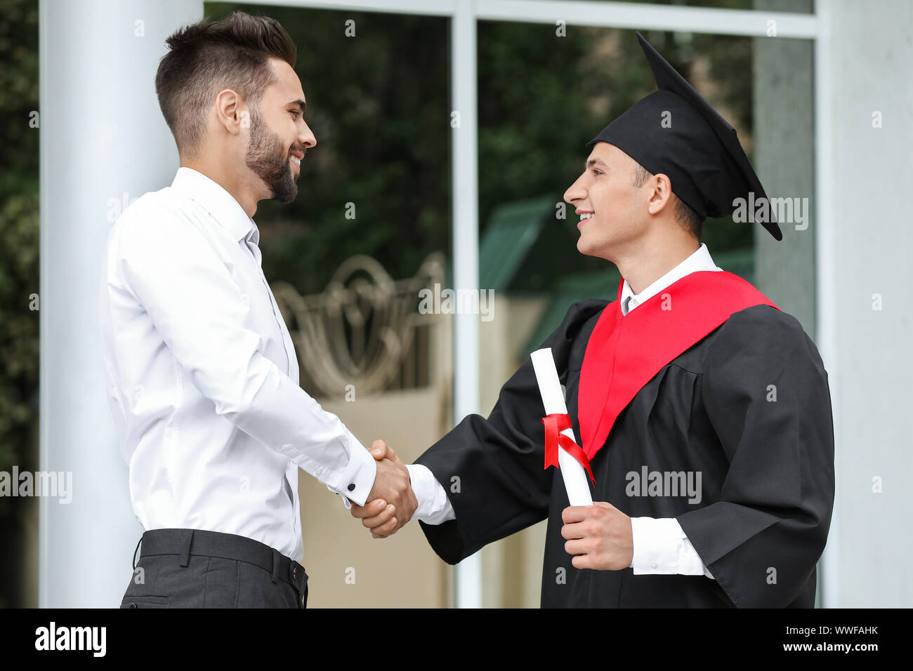 Professor greeting young student on his graduation day Stock Photo - Alamy