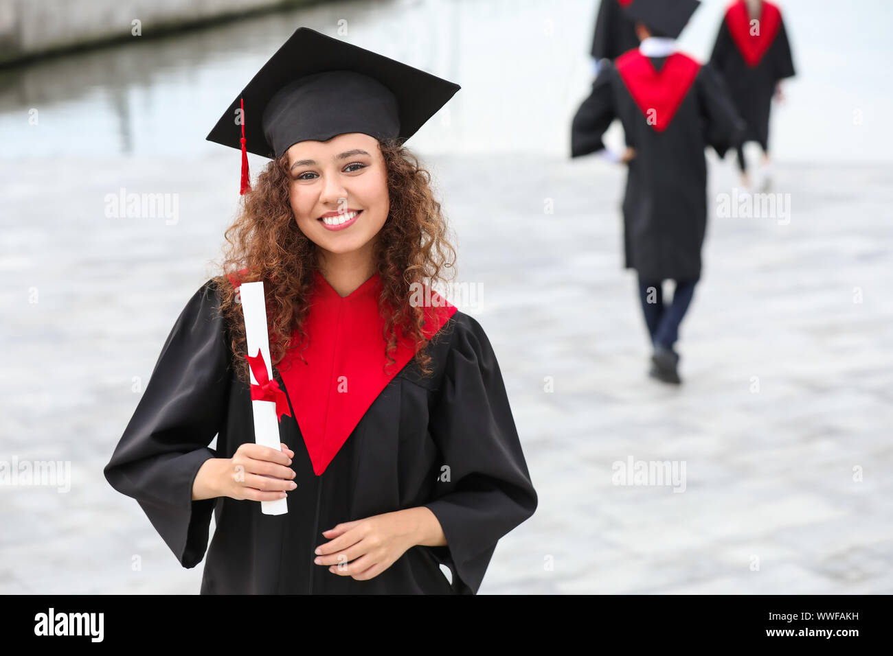 Happy African-American student in bachelor robe and with diploma ...