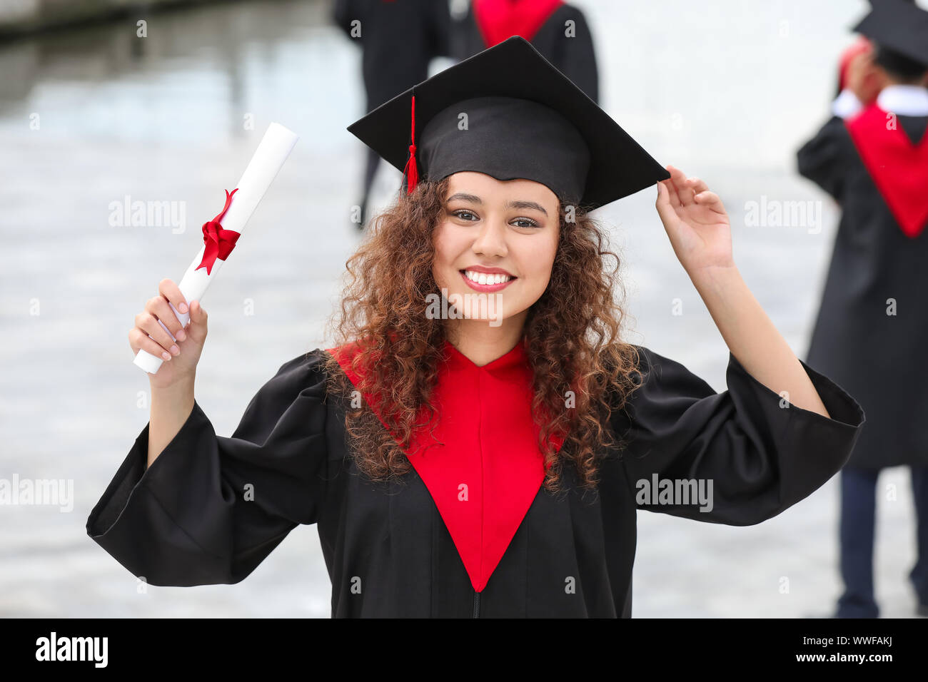 Happy African-American student in bachelor robe and with diploma ...