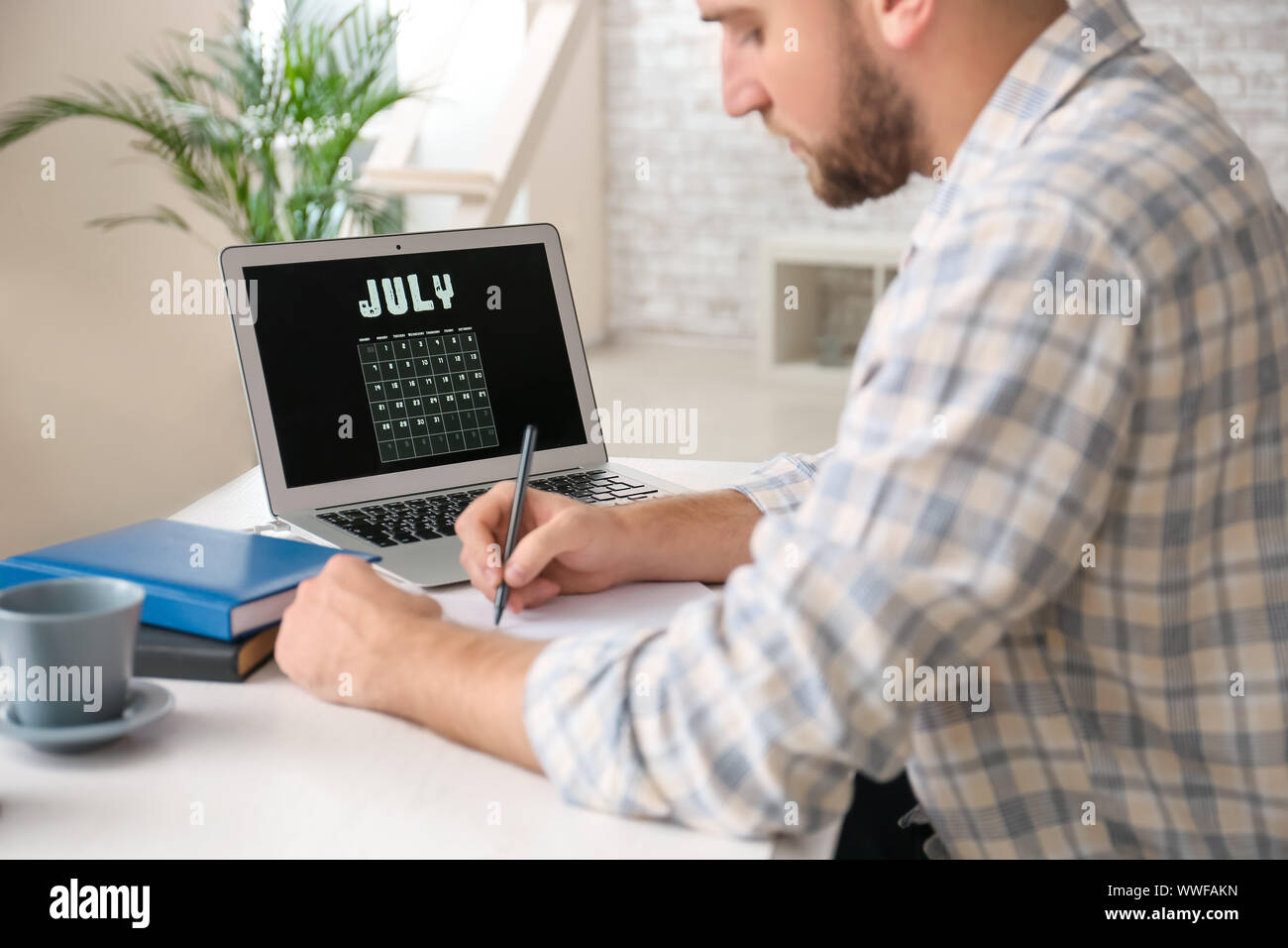 Man using calendar on laptop screen while working in office Stock Photo ...