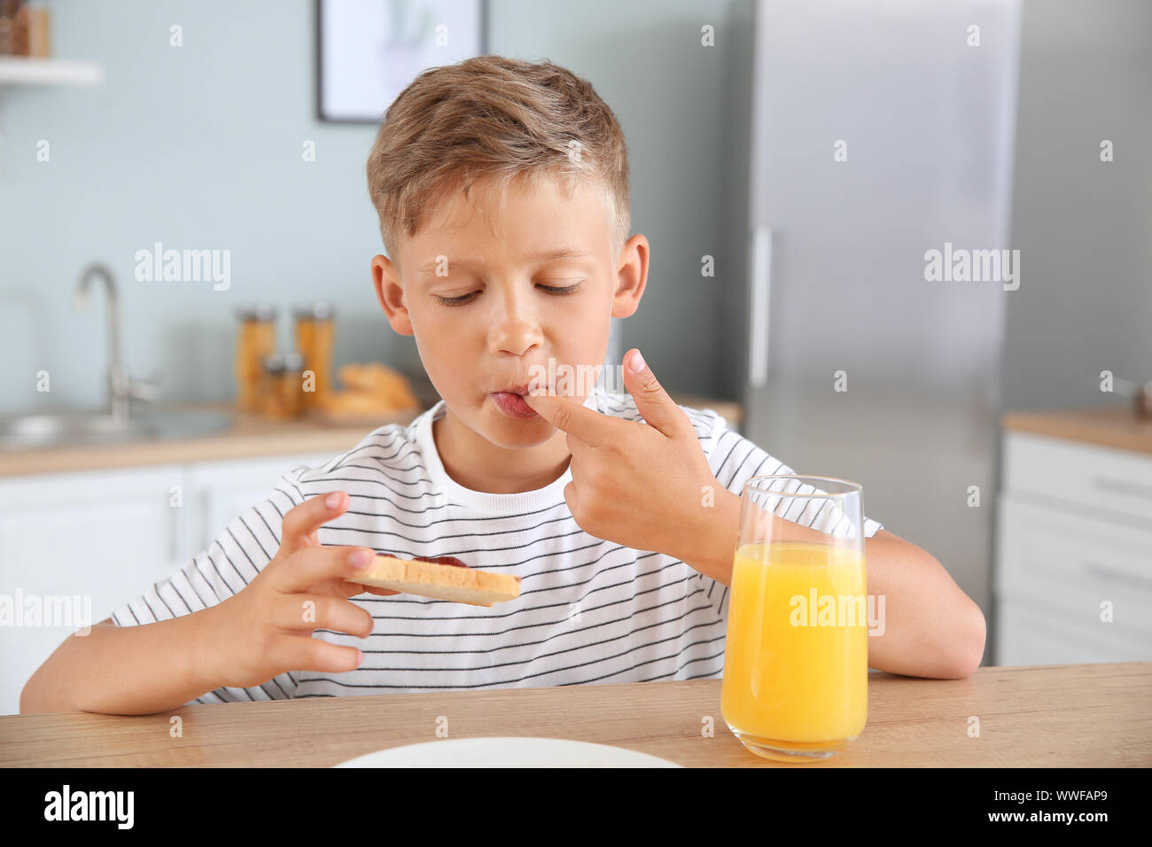 Funny little boy eating tasty toasts with jam in kitchen Stock Photo ...