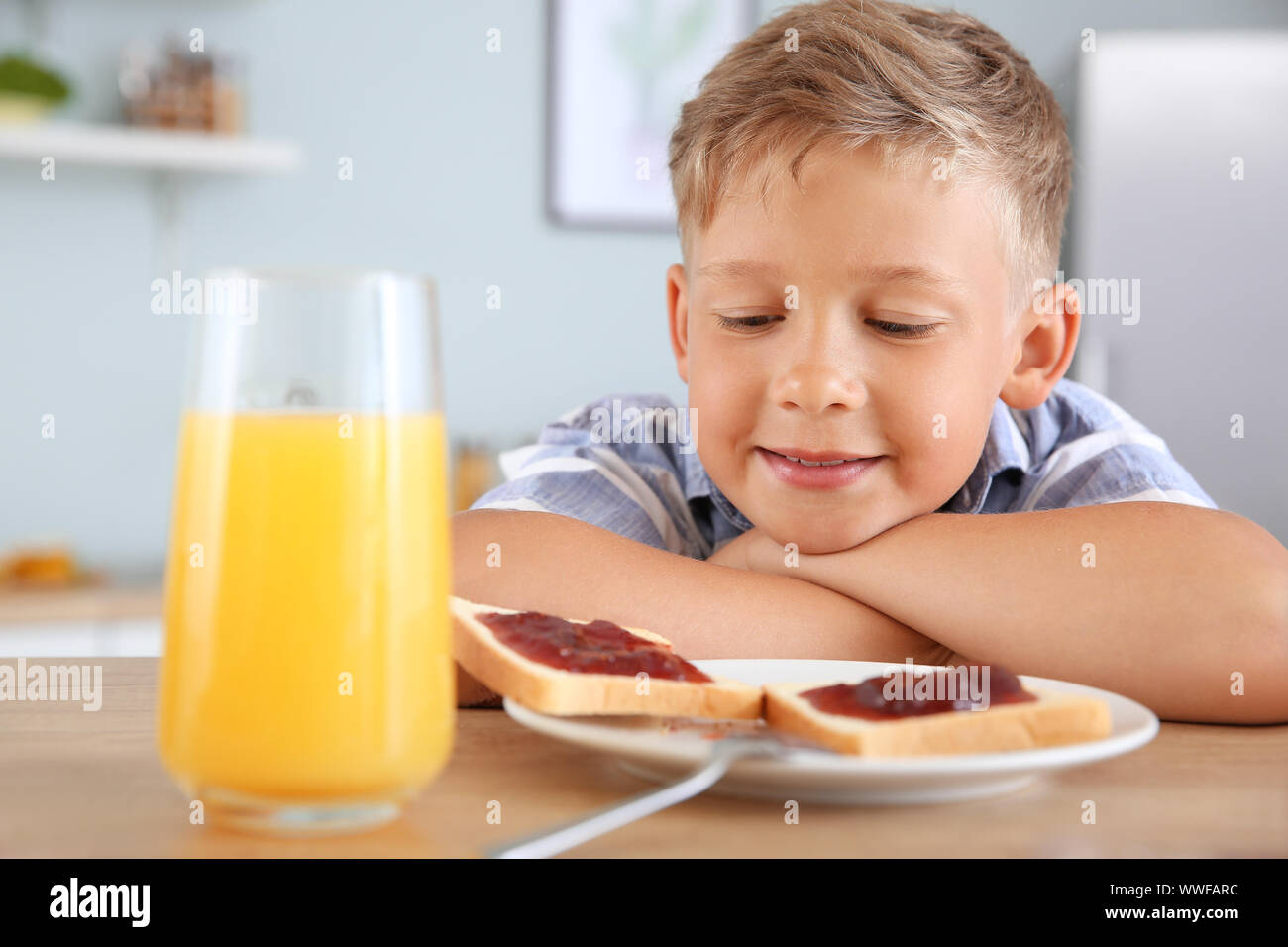 Funny little boy eating tasty toasts with jam in kitchen Stock Photo ...