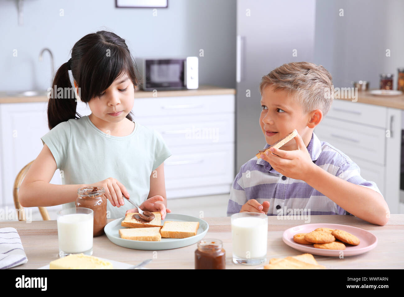Funny little children eating tasty toasts in kitchen Stock Photo - Alamy