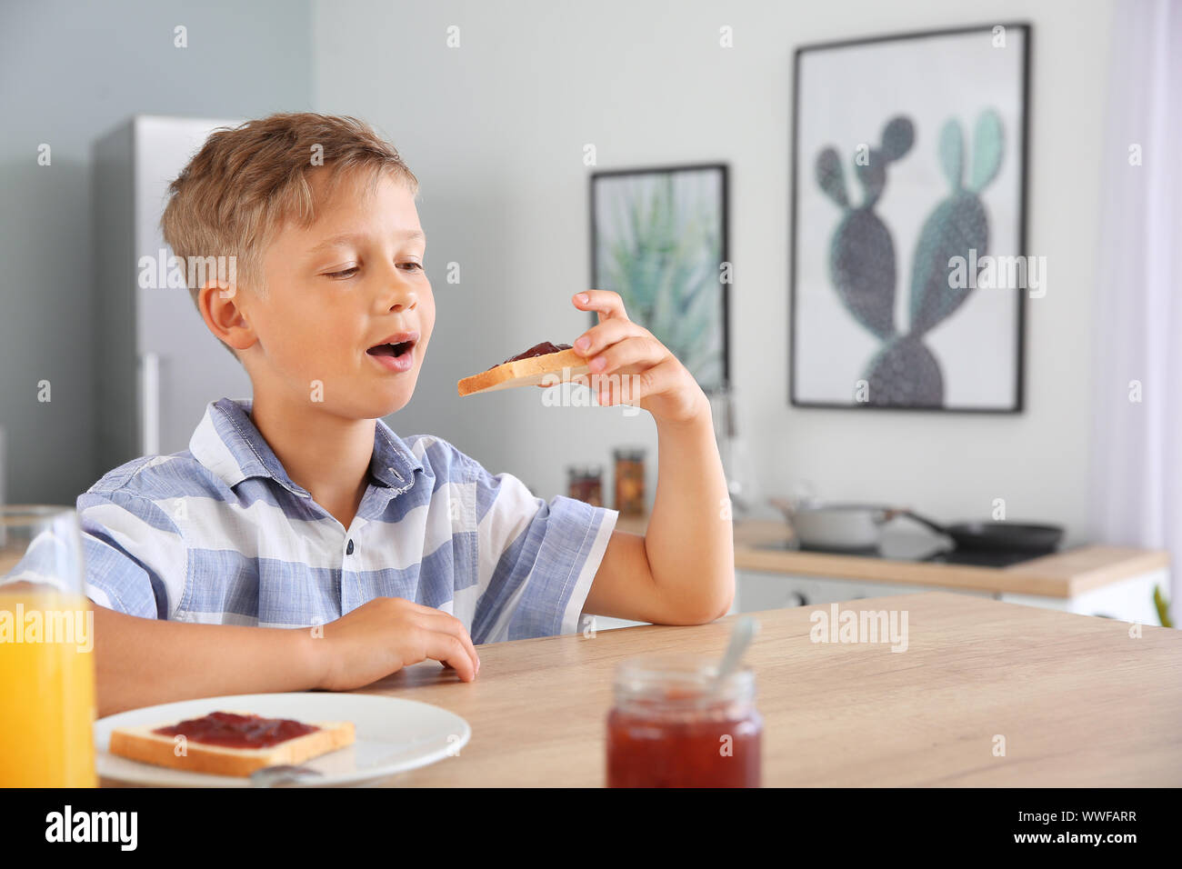Funny little boy eating tasty toasts with jam in kitchen Stock Photo ...