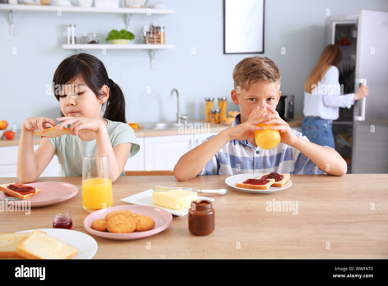 Funny little children eating tasty toasts in kitchen Stock Photo - Alamy