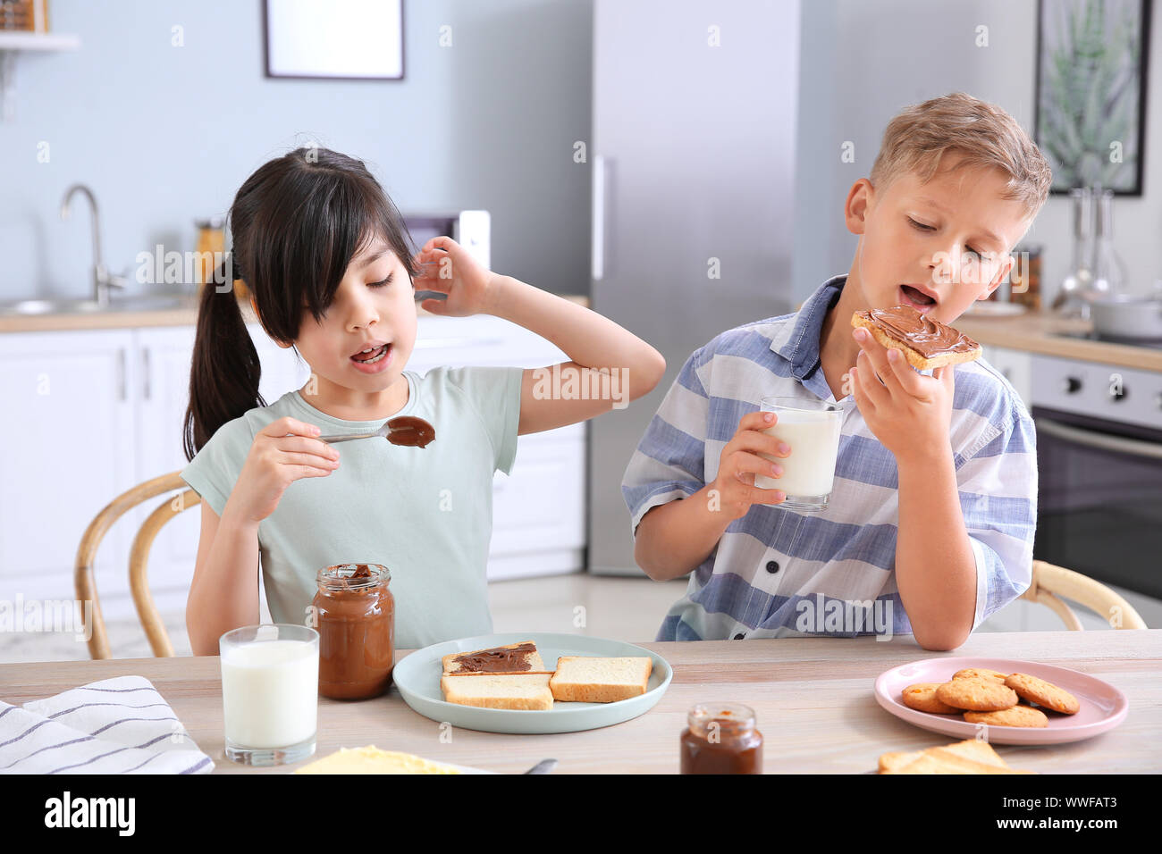 Funny little children eating tasty toasts in kitchen Stock Photo - Alamy
