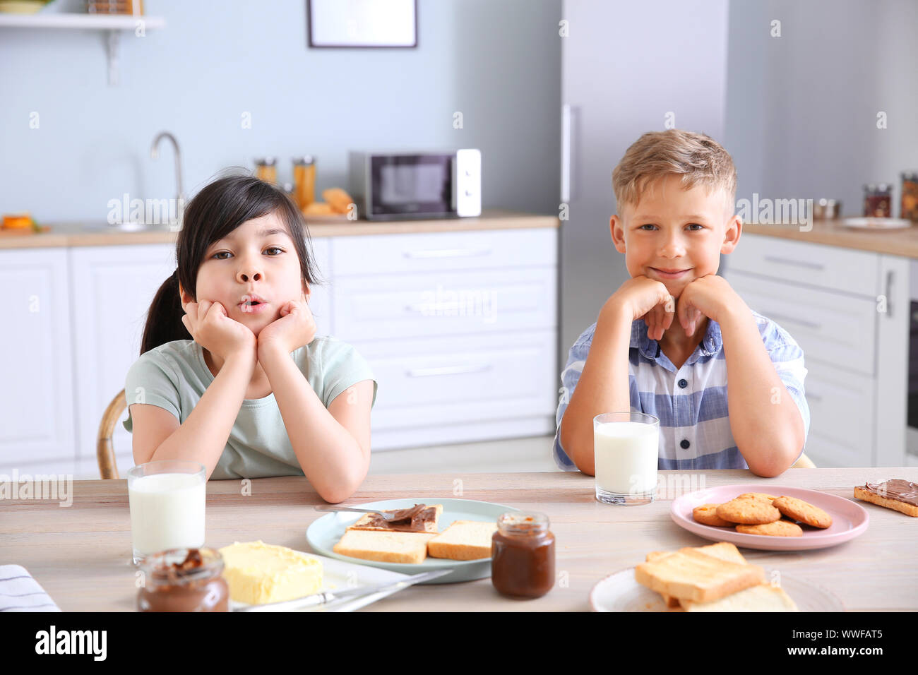 Funny little children eating tasty toasts in kitchen Stock Photo - Alamy
